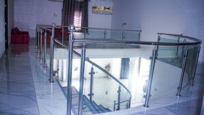 Uma sala de estar espaçosa com escada em vidro que dá acesso a um andar superior.