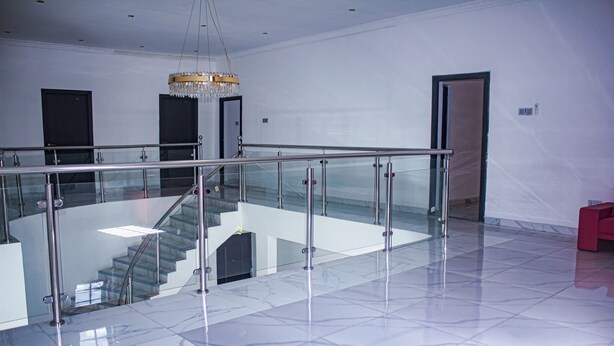 Um hall amplo com guarda-corpo de vidro, piso de mármore e um candelabro.