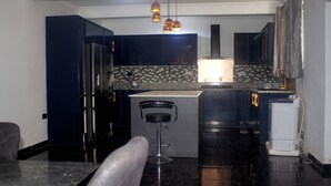 Uma cozinha moderna com armários escuros, um banquinho de bar e bancada.