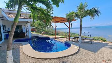 Uma casa moderna com piscina, área de estar externa e vista para o mar.