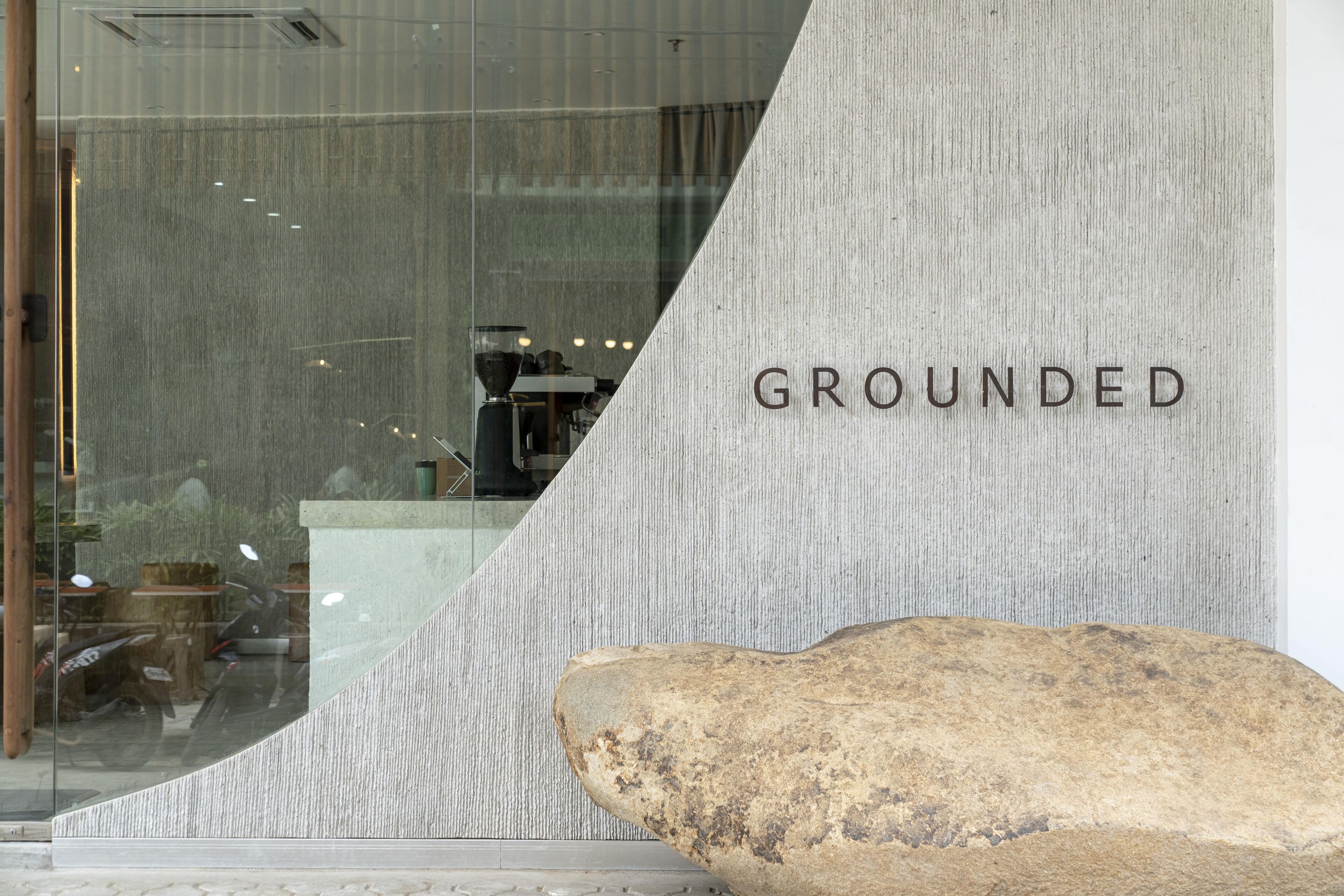 Pareda de pedra com a palavra 'GROUNDED' e uma rocha grande à frente.