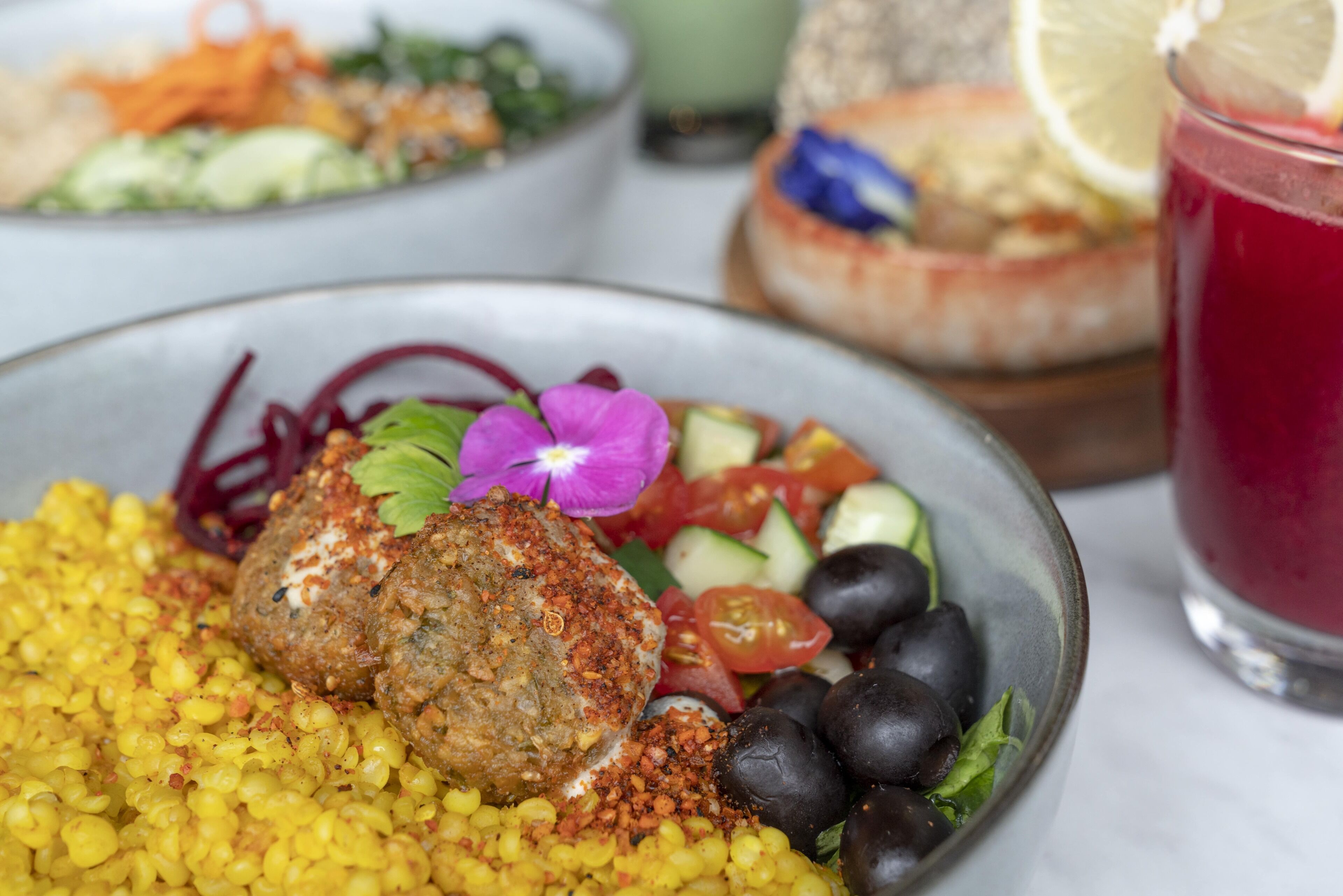Uma refeição com couscous, uma almôndega, vegetais e uma bebida.