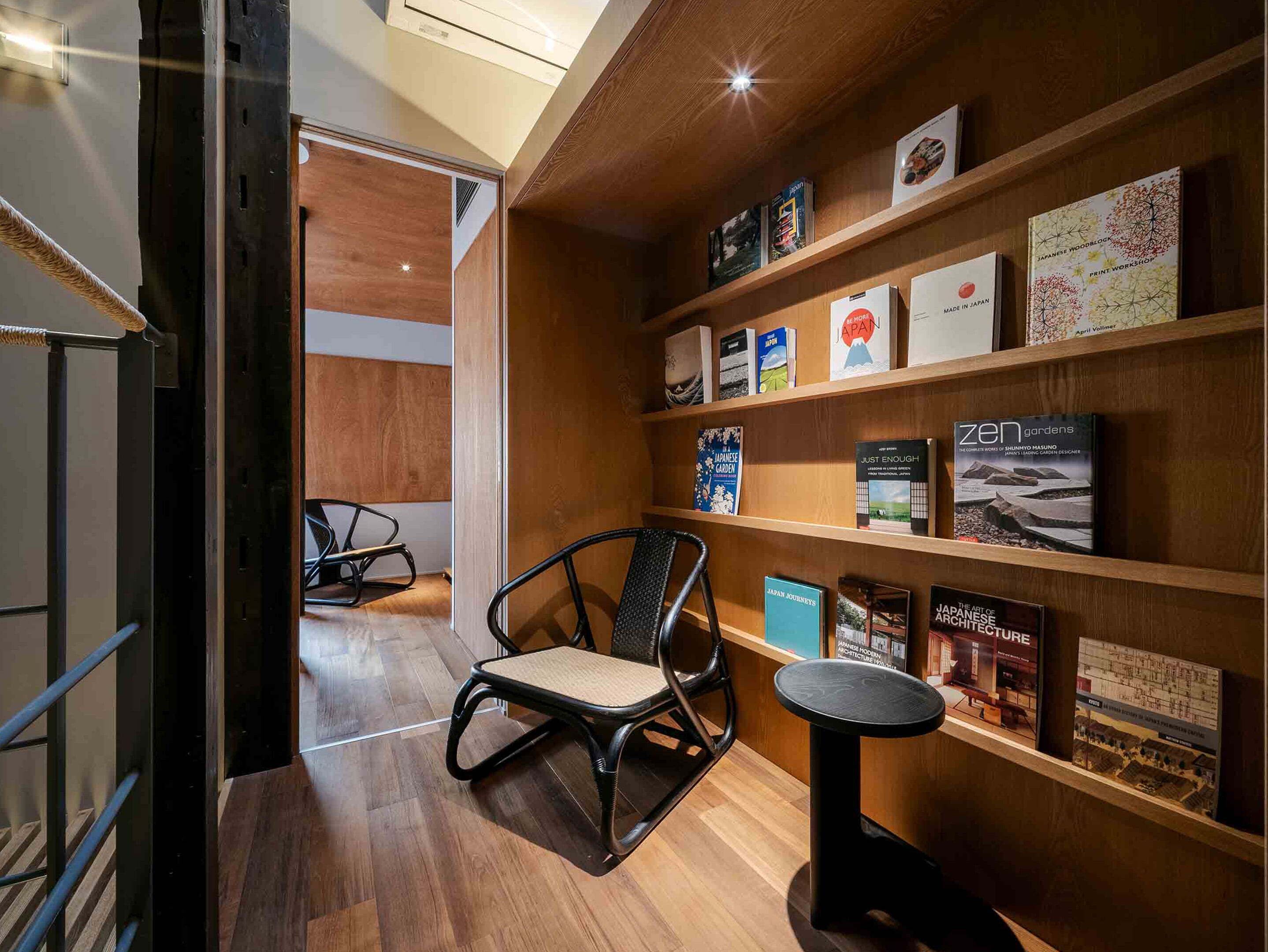 Um interior moderno com uma estante de madeira, uma cadeira preta e uma mesa redonda pequena.