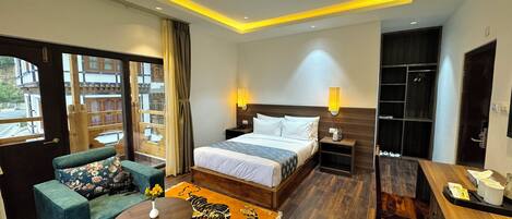 Quarto de hotel com cama, sofá, mesinha, escrivaninha e guarda-roupa.