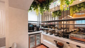 Uma cozinha moderna com teto de tijolos, plantas penduradas e diversos eletrodomésticos e utensílios.