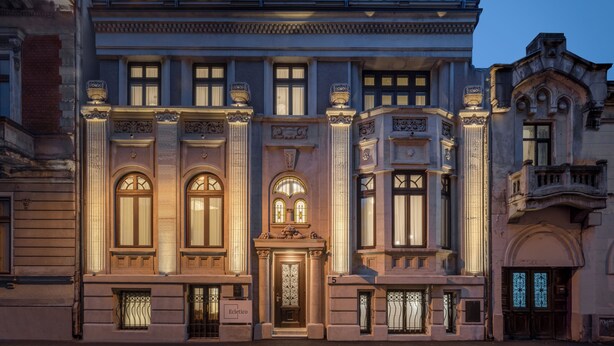 Um edifício histórico com detalhes arquitetônicos elaborados, incluindo janelas em arco e molduras decorativas.