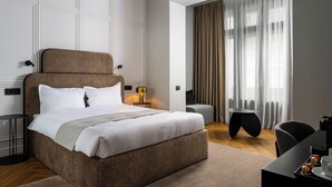 Quarto de hotel moderno com uma cama grande, uma mesa e uma cadeira.