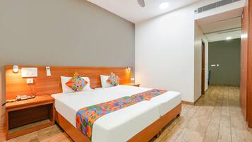 Quarto de hotel com uma cama grande, cabeceira de madeira, mesas de cabeceira e um ventilador de teto.