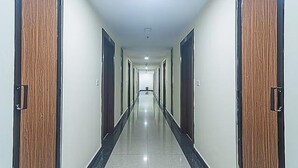 Um corredor comprido e estreito, com portas de madeira em ambos os lados e um chão de azulejos brilhantes.