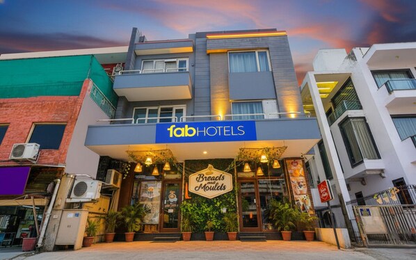 Fachada de hotel com uma placa indicando "fab hotels" e "Breaths and Moulds".