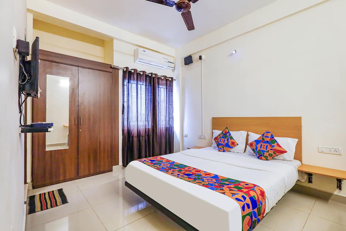 Quarto com cama, guarda-roupa de madeira, televisão e ventoinha no teto.