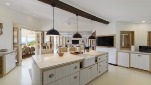 Cozinha moderna com ilha central, iluminação pendente e vista para o exterior.