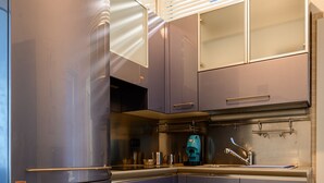 Uma cozinha moderna com armários azul escuro, eletrodomésticos de aço inoxidável e painel de azulejos.