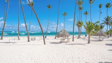 Na praia, areia branca, guarda-sóis, toalhas de praia