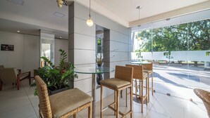 Um interior moderno com uma mesa de jantar de vidro, cadeiras de vime e um vaso com planta.