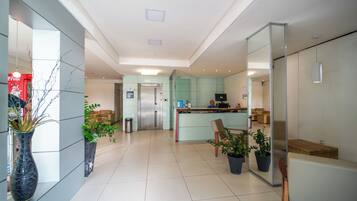 Um lobby moderno de hotel com balcão de recepção, área de estar e divisória de vidro.