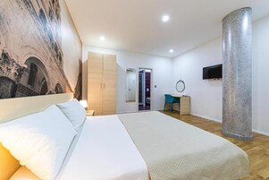 Quarto de hotel moderno com uma cama grande, uma escrivaninha, um espelho e um pilar de pedra.