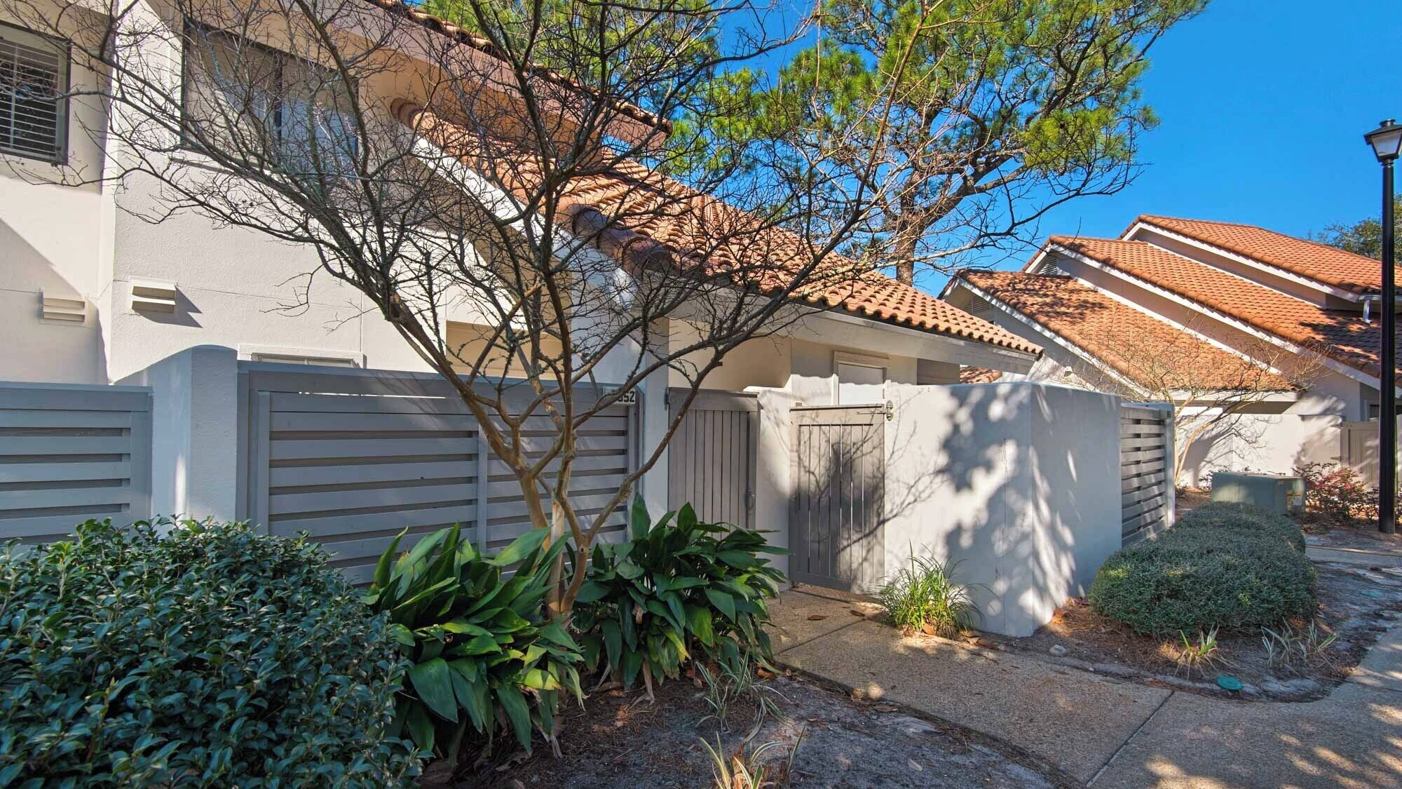 Um imóvel residencial com fachada branca, telhado telhado e entrada com portão.