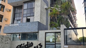 Um edifício moderno com fachada em azulejos, entrada visível com degraus e uma placa com a inscrição "Studio 413".