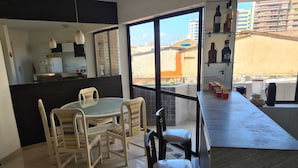 Cozinha moderna com área de refeições, janelas amplas e vista para edifícios.