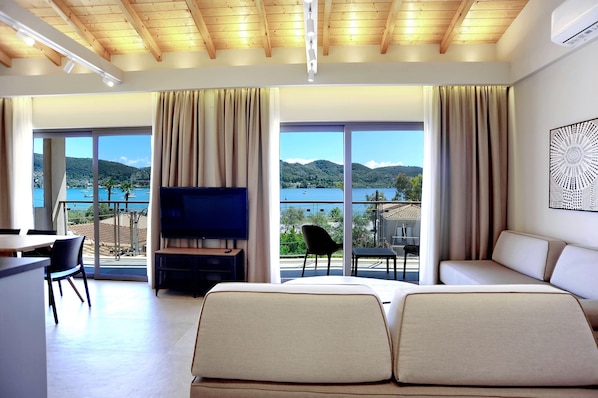 Quarto de hotel com uma cama grande, televisão e varanda com vista para o mar.