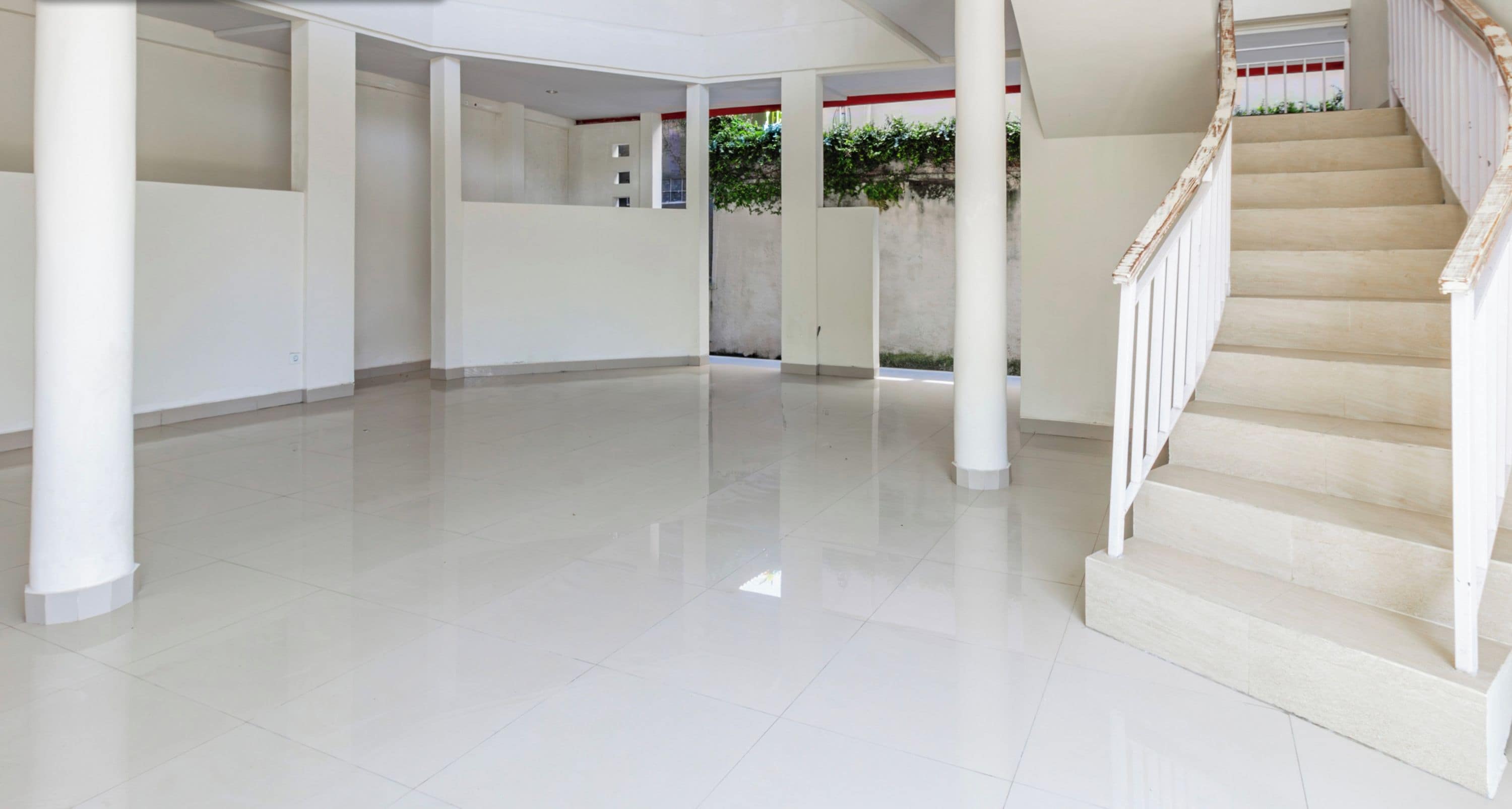 Um interior espaçoso e moderno, com área central aberta, escadaria e corredor com colunas.