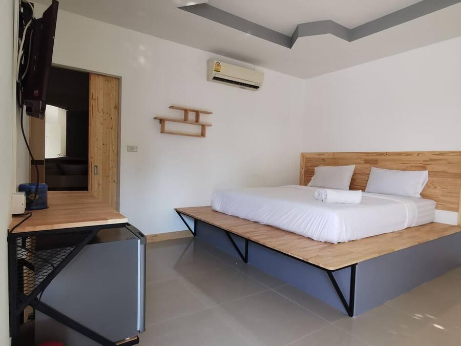 Quarto moderno com cama, televisão e uma pequena mesa de escritório.