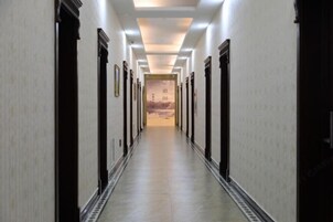 Um corredor comprido e estreito, com portas em ambos os lados, que dá para um quarto com vista para uma paisagem desértica.