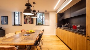 Uma cozinha moderna com armários de madeira, bancada preta e área de refeições com mesa e cadeiras de madeira.