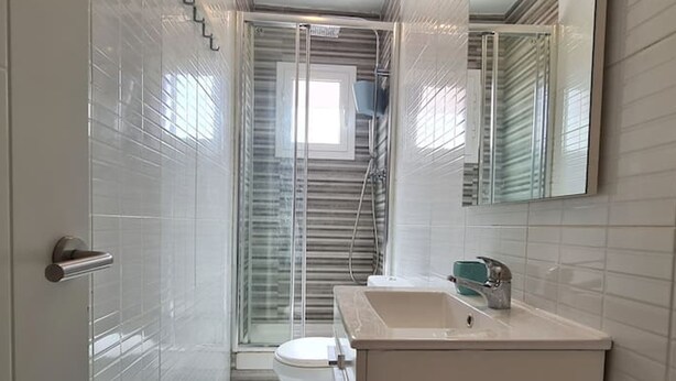 Uma casa de banho moderna com sanita, lavatório e chuveiro.