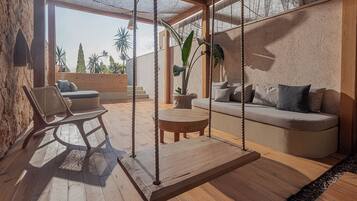 Um interior moderno com piso de madeira, uma cadeira balanço, um sofá e uma planta em vaso.