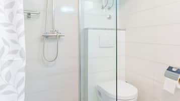 Uma casa de banho moderna com chuveiro em cabine de vidro, sanita branca e aquecedor fixado na parede.