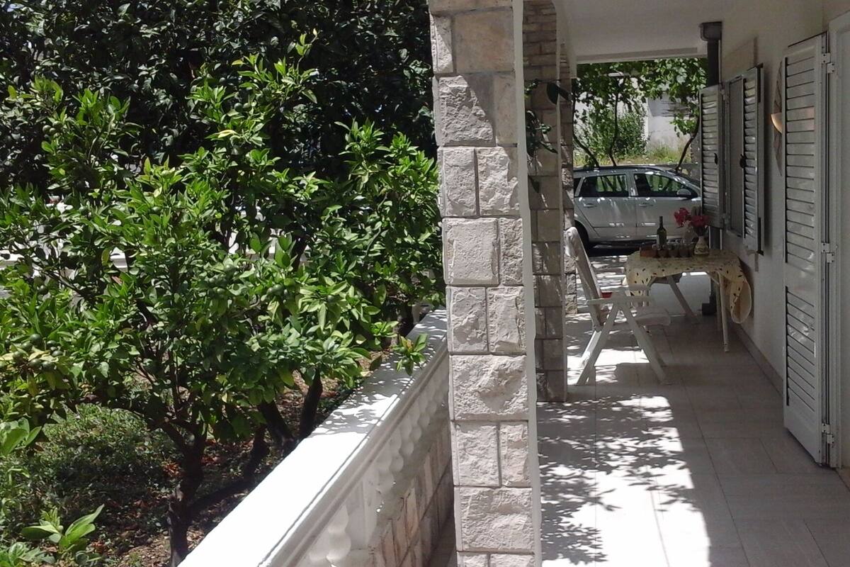 Uma área externa coberta com um pilar de pedra, uma mesa com toalha e um carro estacionado.