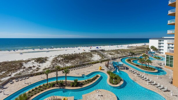 Um resort com uma extensa área de piscina, uma praia e um edifício com varandas.