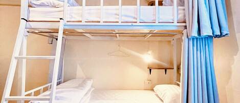 Uma cama beliche com escada, roupa de cama branca e luminária fixada na parede.