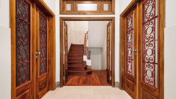 Um corredor com portas de madeira e uma escada que leva a um andar superior.