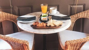 Uma mesa de jantar com pratos, croissants, um copo de sumo de laranja e uma chávena de café.