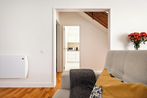 Uma sala de estar moderna com um sofá cinzento, piso de madeira e radiador branco.
