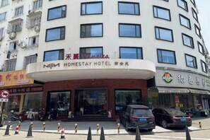 Um edifício de vários andares com uma placa visível para o Homestay Hotel.
