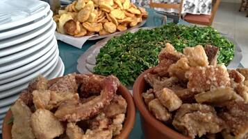 Uma mesa com pratos de comida frita, incluindo frango crocante e batatas rústicas.