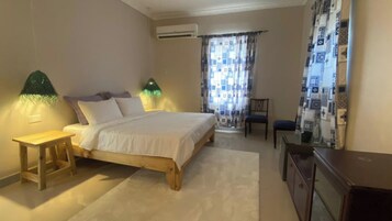 Um quarto com cama, mesas de cabeceira, escrivaninha, cadeira e guarda-roupa.