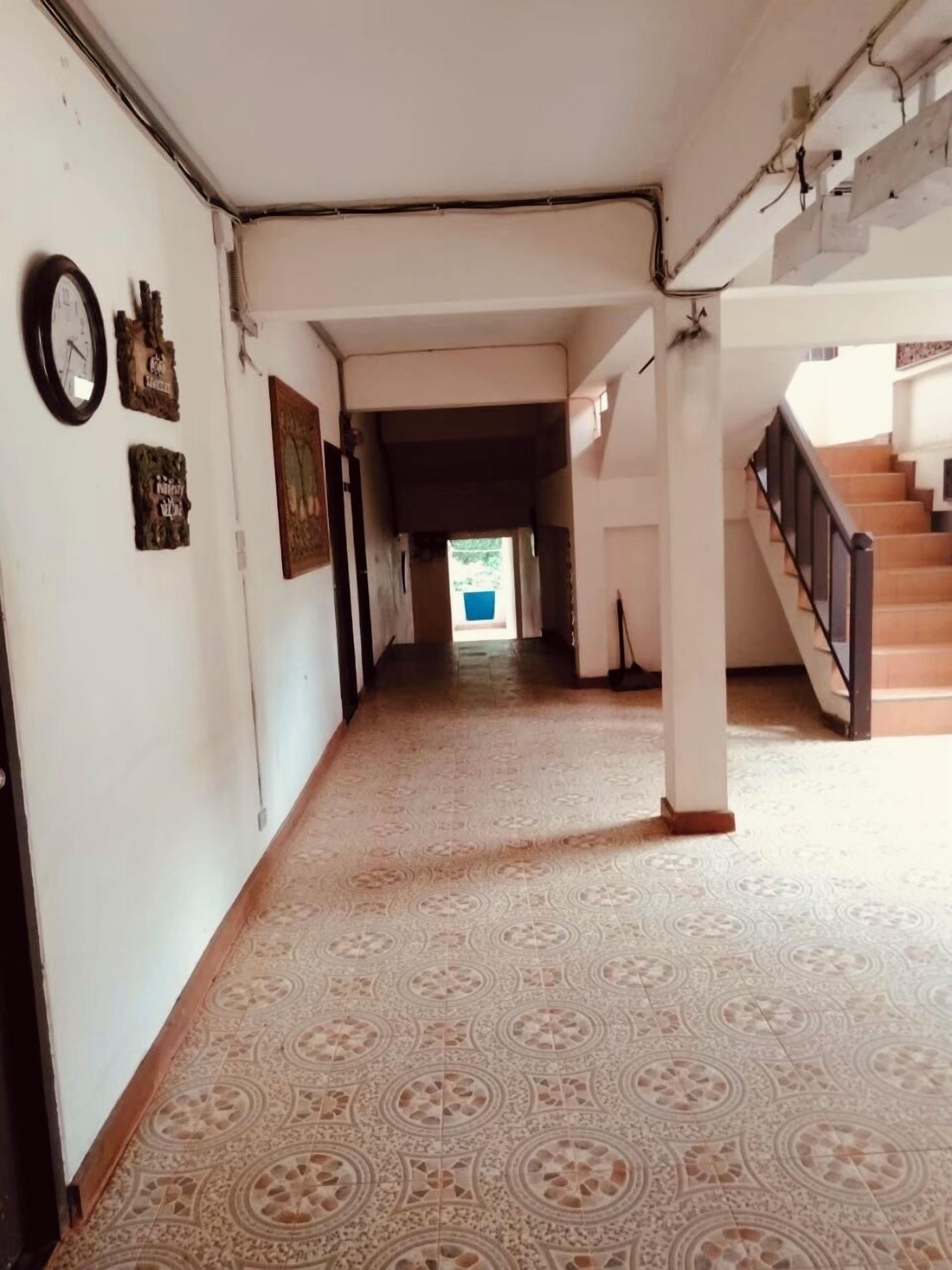Um corredor com piso estampado, escada e porta que dá acesso a outro cômodo.