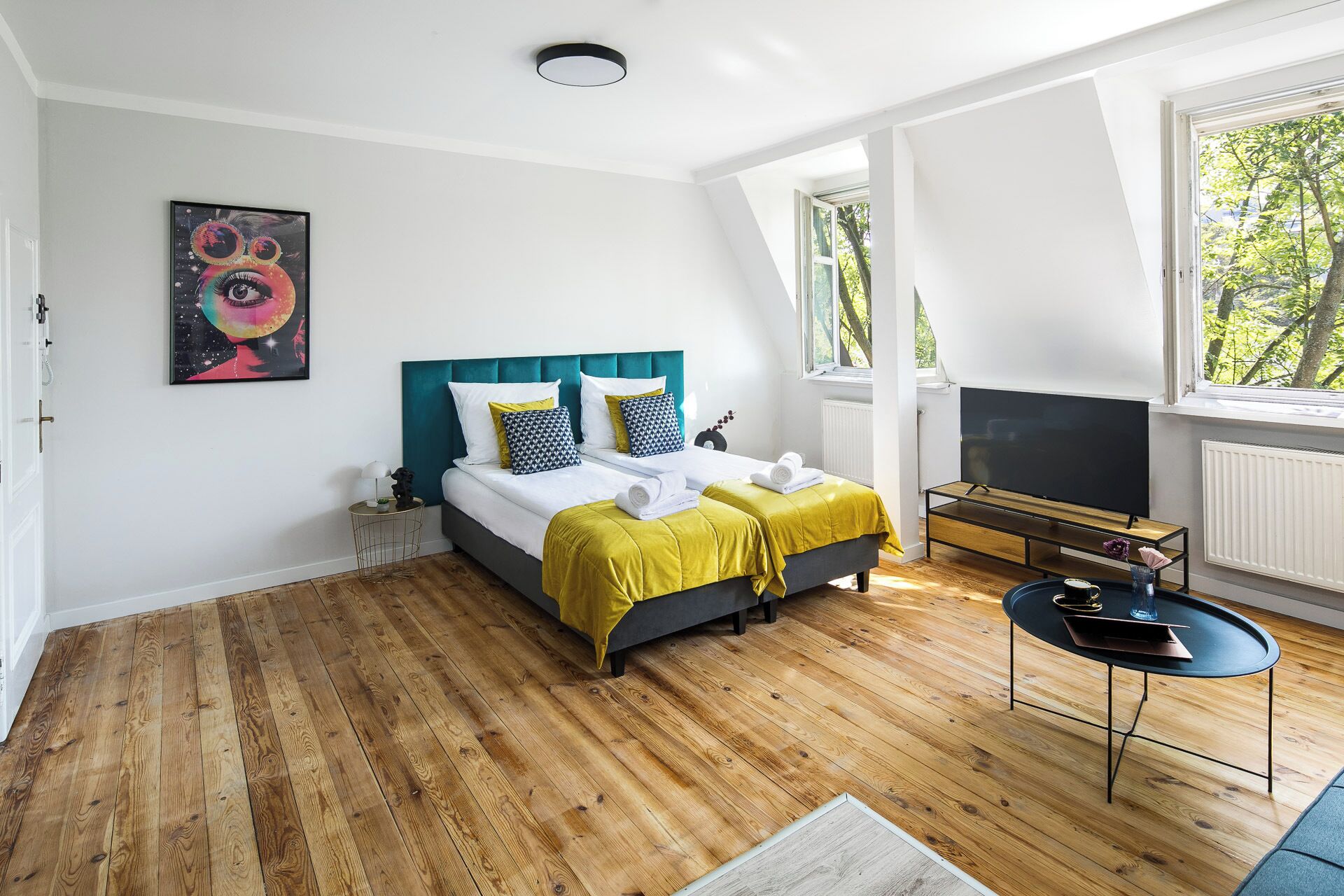 Quarto moderno com cama, mesa de cabeceira e televisão.