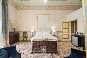 Um quarto luxuoso com uma cama grande, uma cômoda de madeira, uma escrivaninha e uma cadeira.