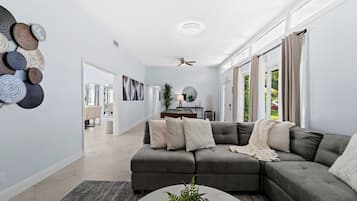 Uma sala de estar moderna com um sofá seccional, uma mesa de centro e uma parede decorativa.