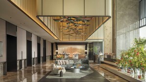 Um lobby moderno com balcão de recepção, área de estar e detalhes decorativos.