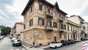 Um edifício histórico com fachada de pedra, várias varandas e uma placa de estacionamento indicando zona proibida.