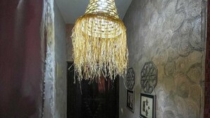 Um corredor com luminária pendente trançada, uma porta no final e arte decorativa na parede.