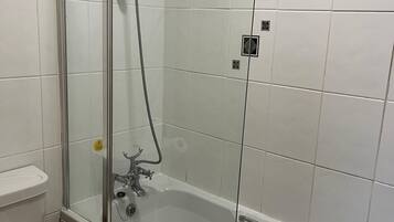 Um banheiro com chuveiro em box de vidro, vaso sanitário branco e banheira.