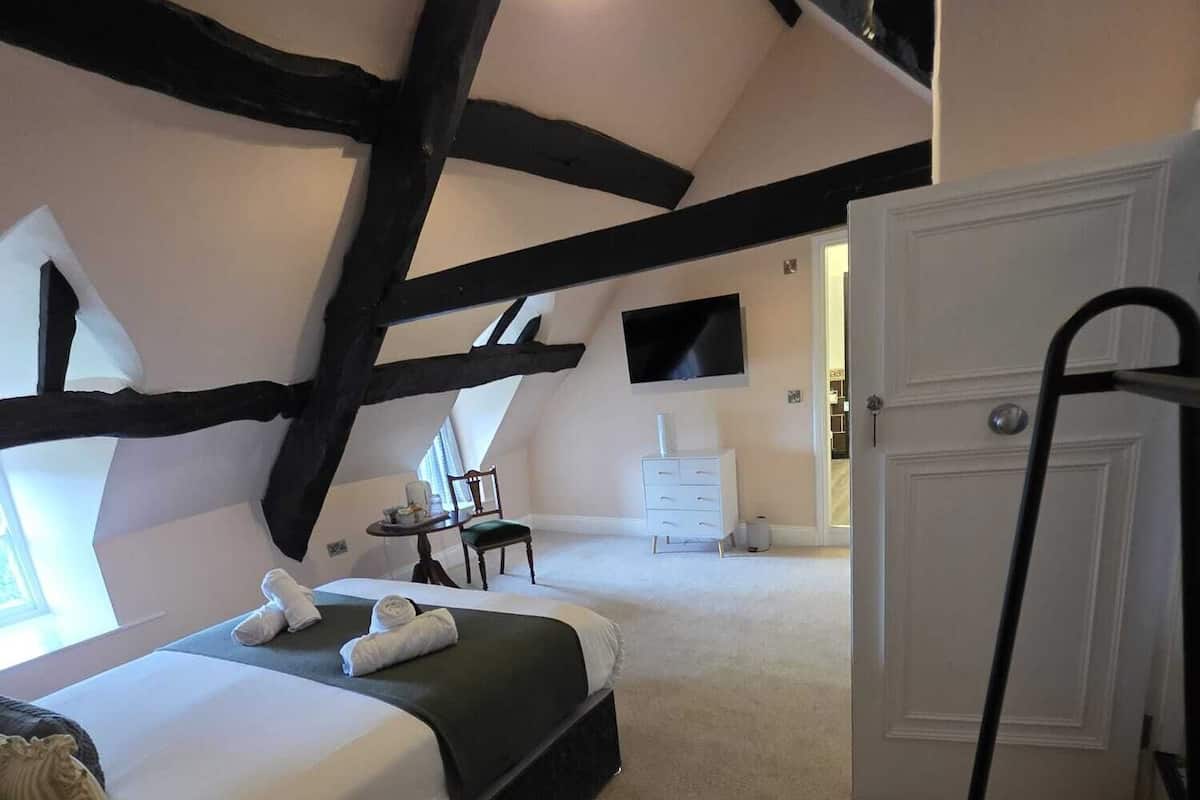 Quarto com cama, poltrona, cômoda e porta.